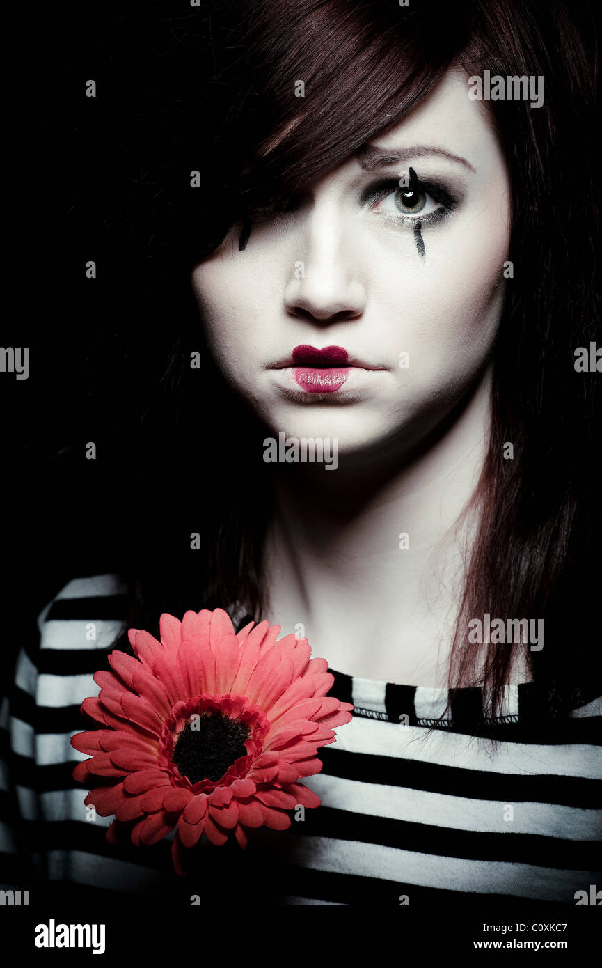 a sad female mime clown with a red flower Stock Photo - Alamy