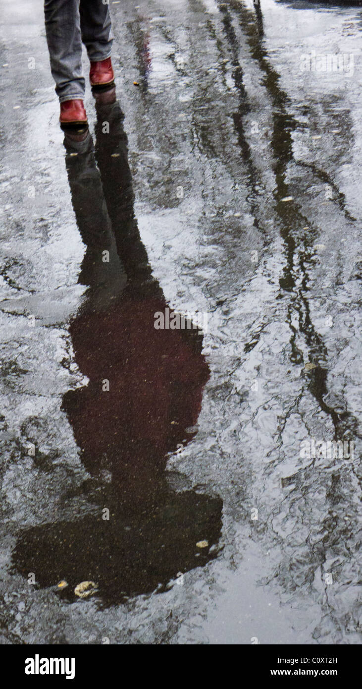 A woman walking across a wet street Stock Photo - Alamy