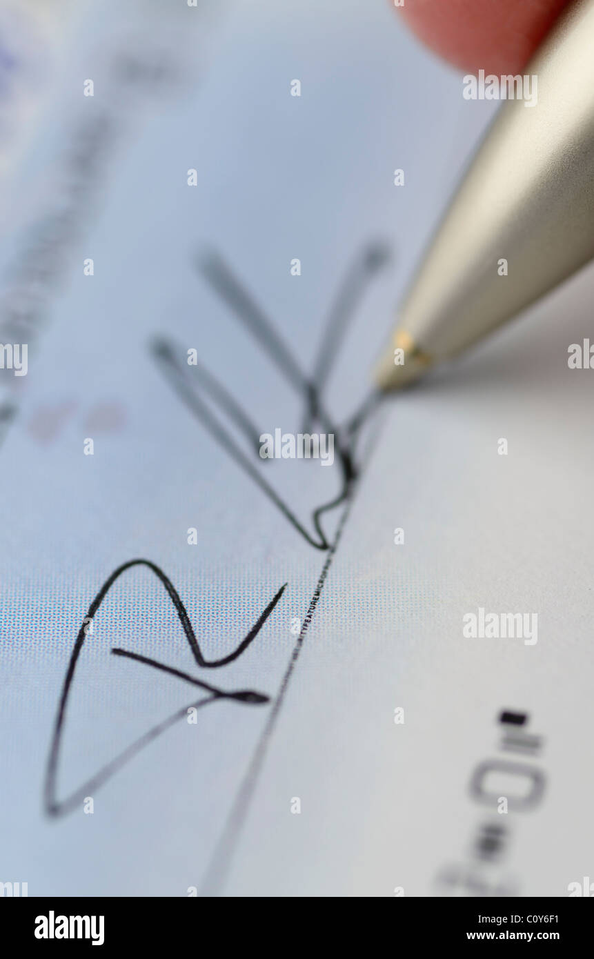 Vertical close up of pen signing a cheque with microprint security ...