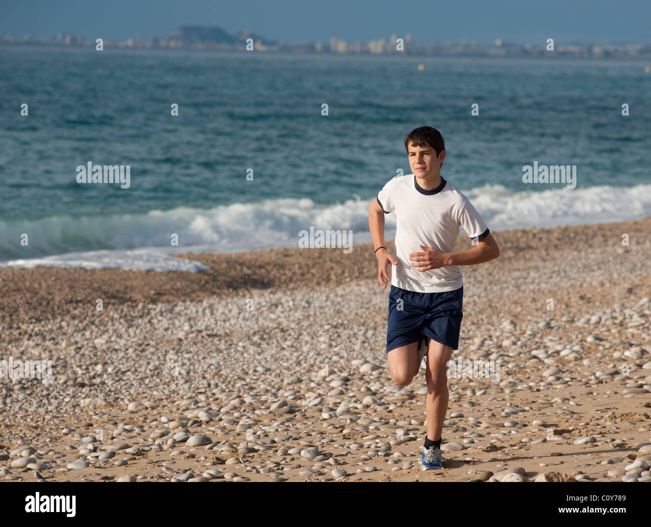 Fit teenager jogging early morning on the beach Stock Photo - Alamy