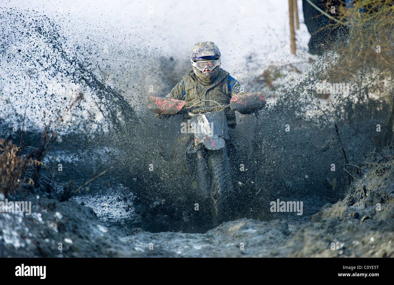 Man on muddy motocross scrambling motorcycle riding through puddle hole ...