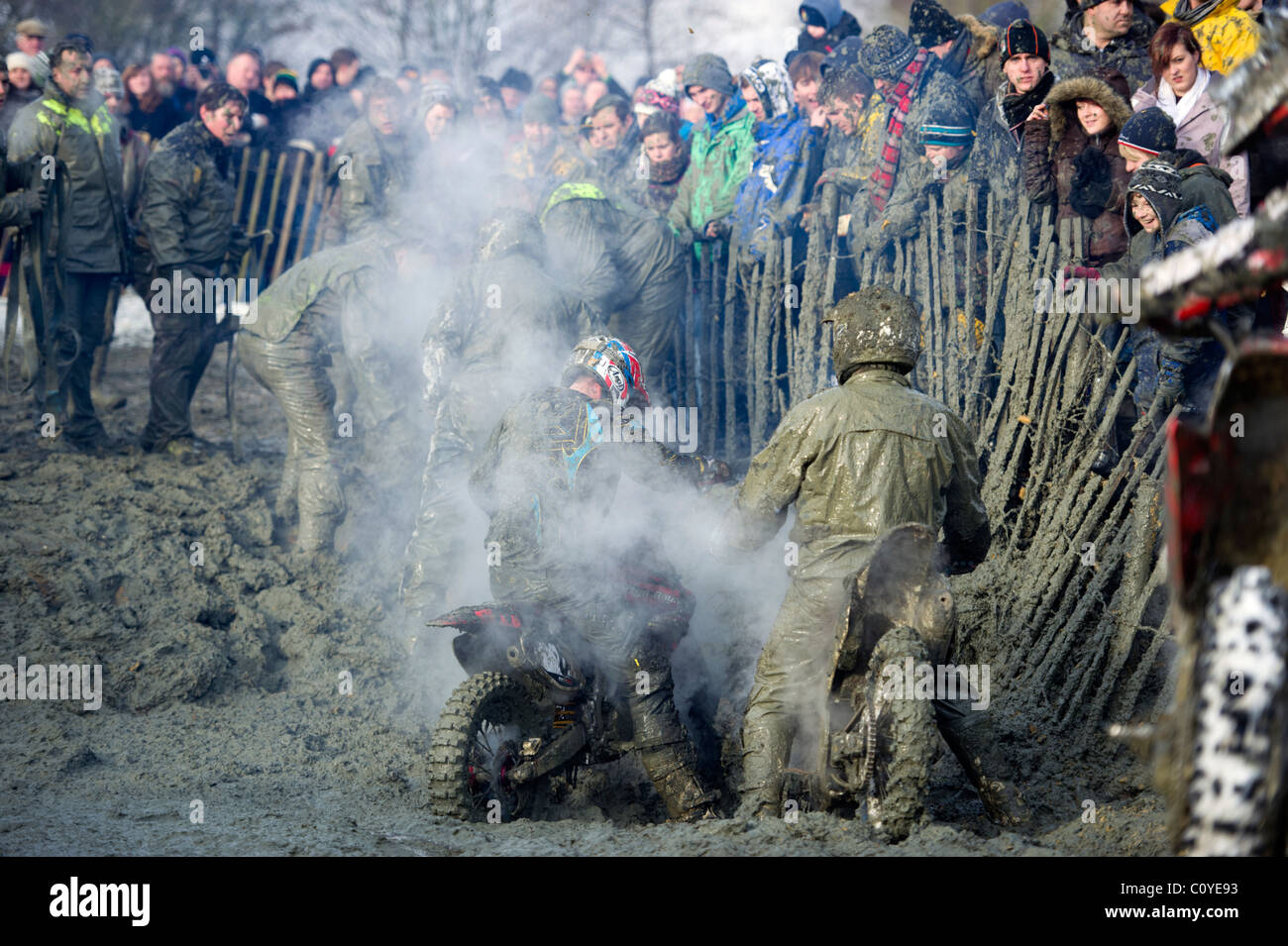 Man on muddy motocross scrambling motorcycle pulled by rope and team of ...