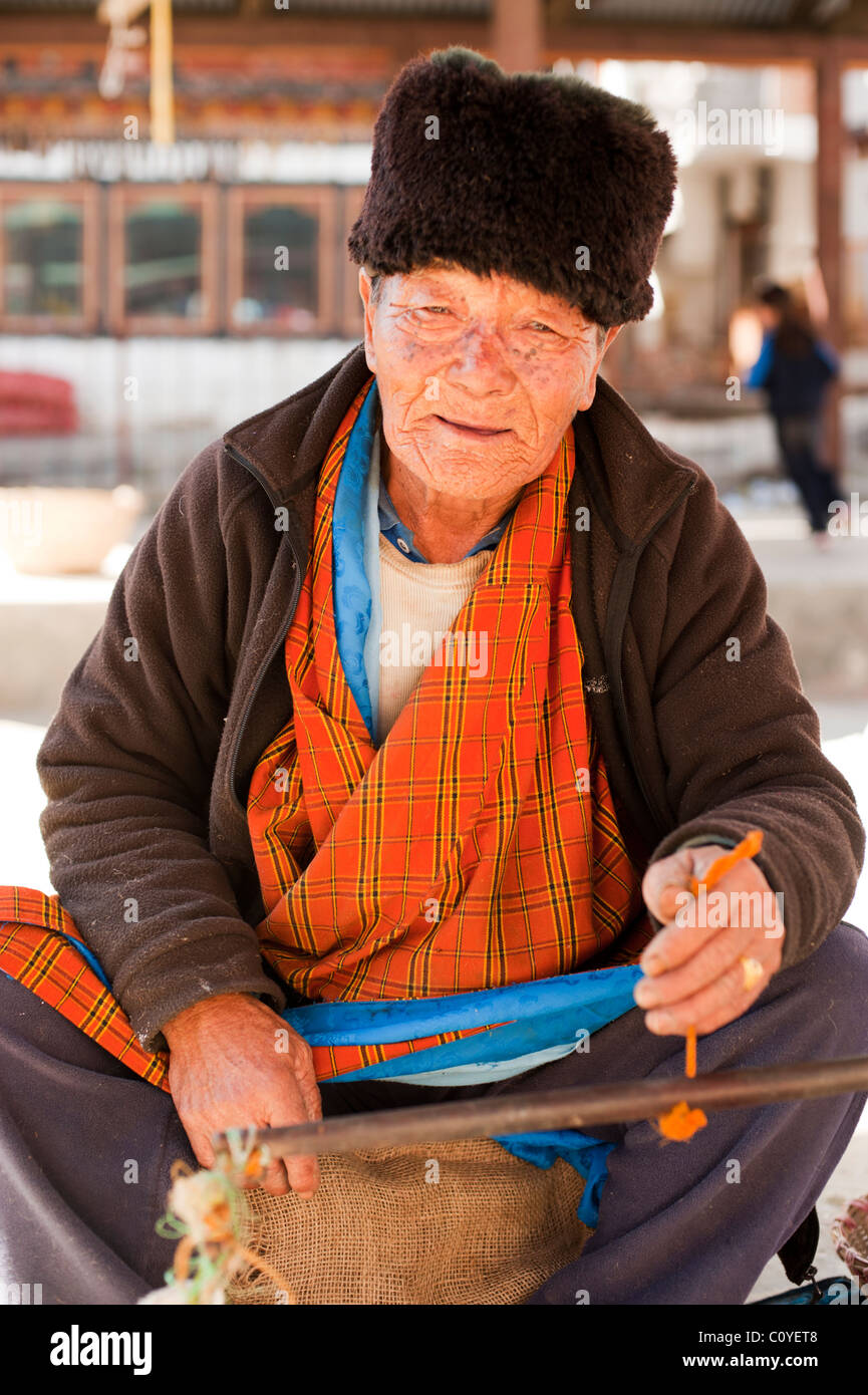 Elderly Bhutanese man in a fur cap selling his wares in the Paro ...
