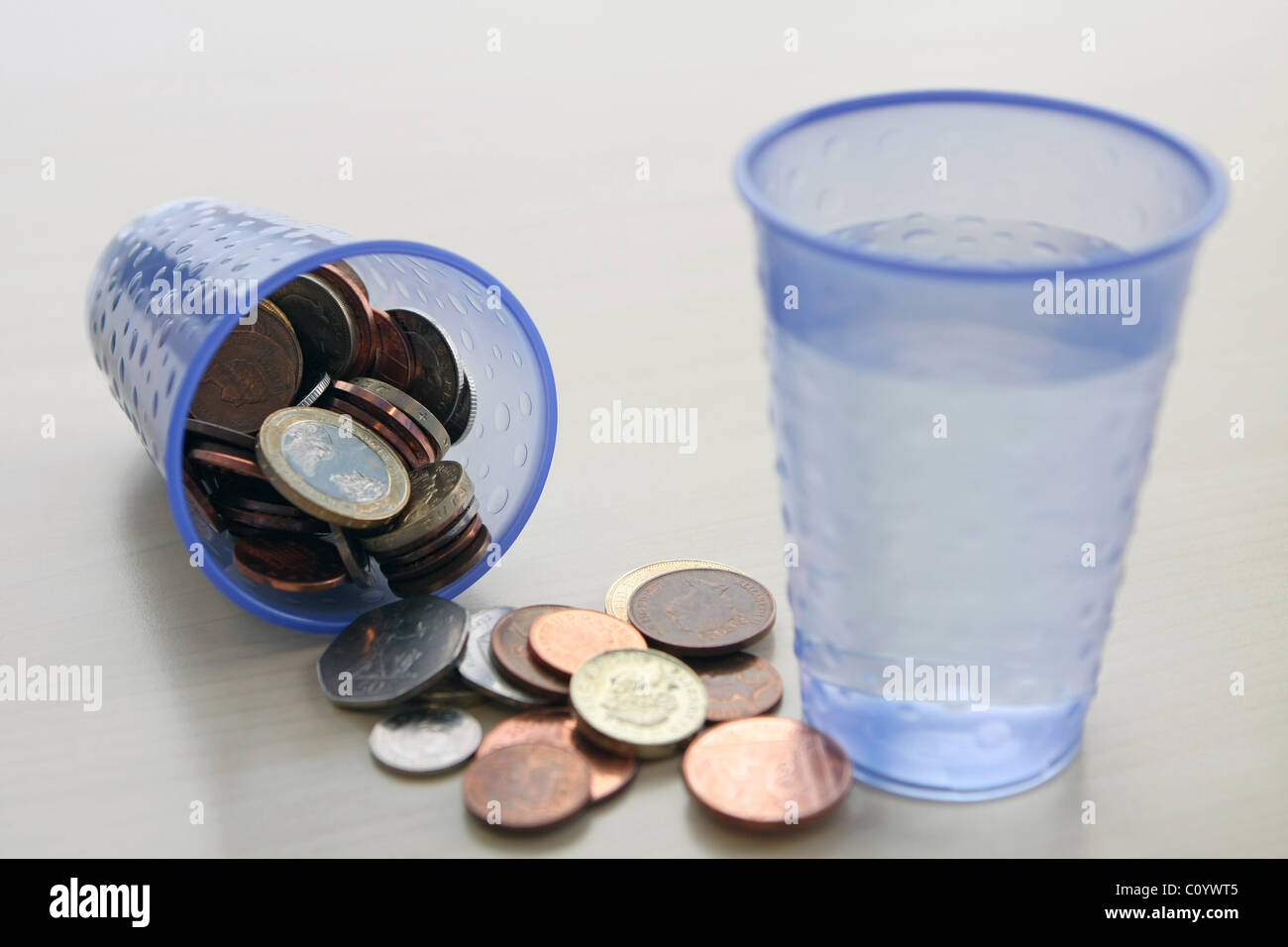 A plastic cup of water and an upturned cup of sterling coins Stock ...