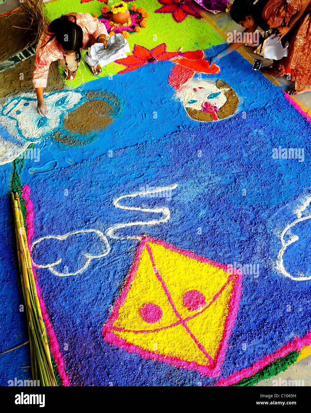 An Indian woman uses colored powder to mark out a Rangoli, a ...