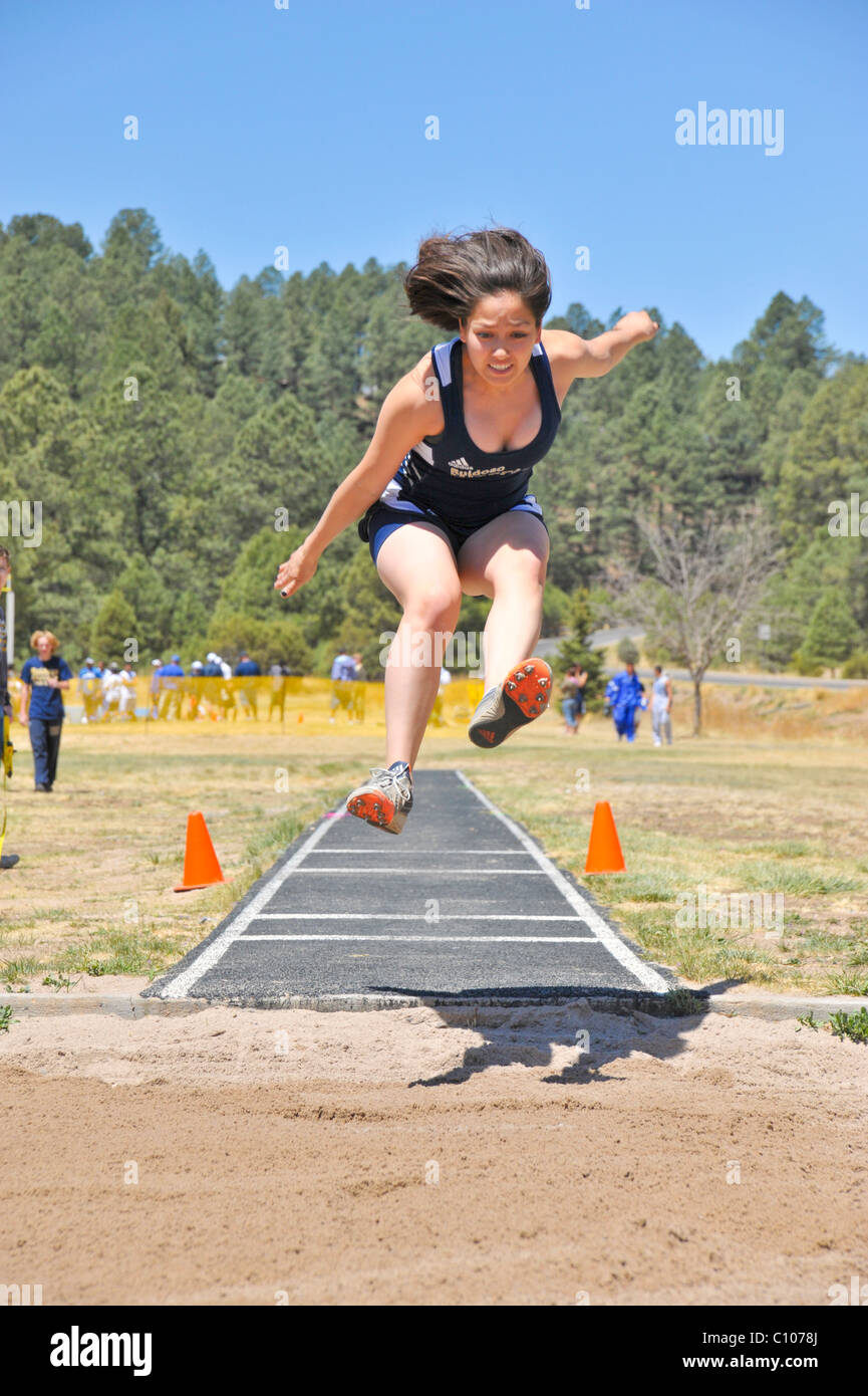 Teenage high school girl athlete soaring in the long jump athletic ...