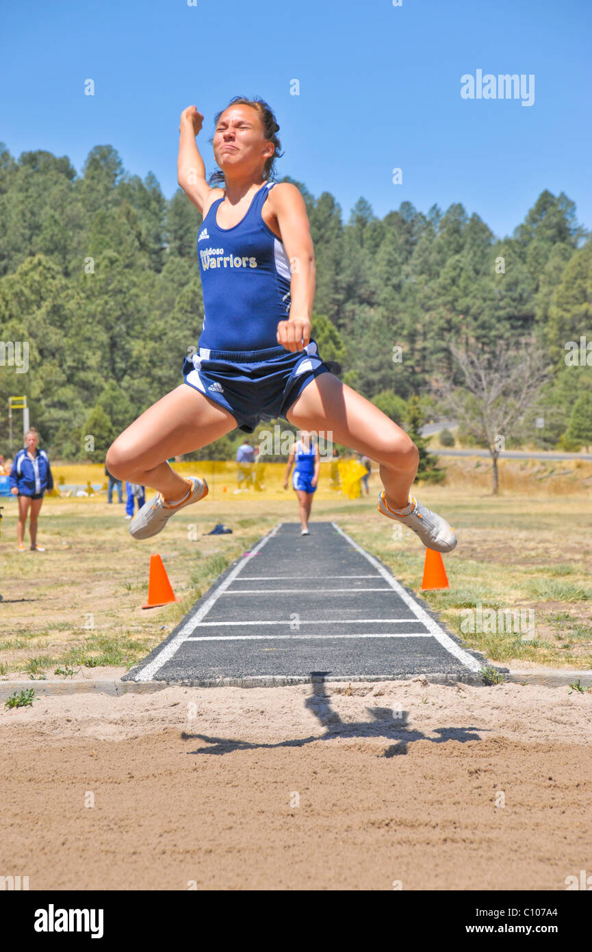 Teenage high school girl athlete soaring in the long jump athletic ...
