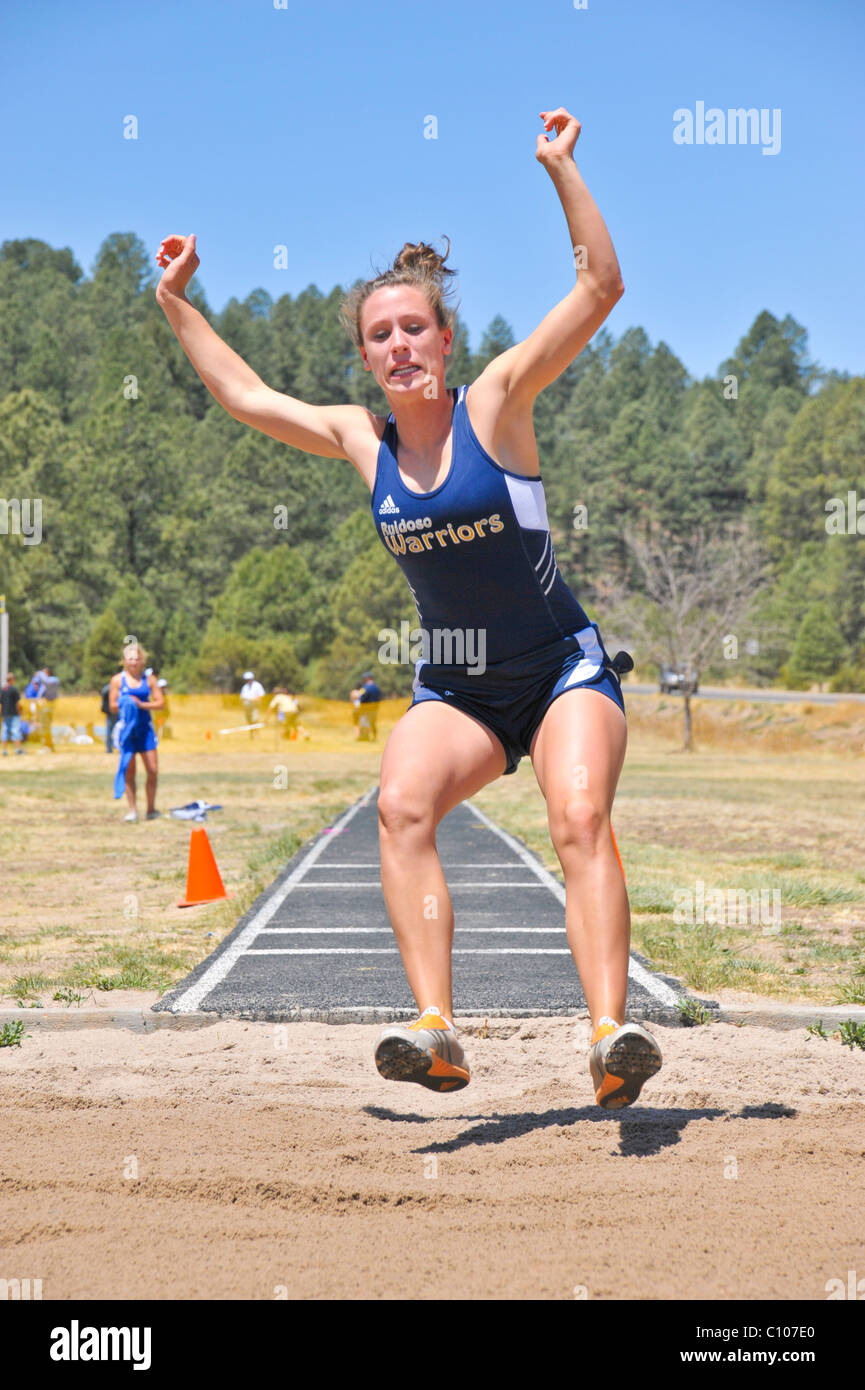 Teenage high school girl athlete soaring in the long jump athletic ...