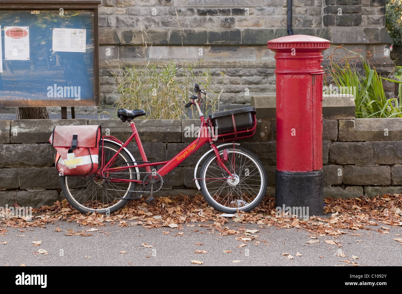 A Royal Mail bicycle propped next to a pillar box and against the wall ...