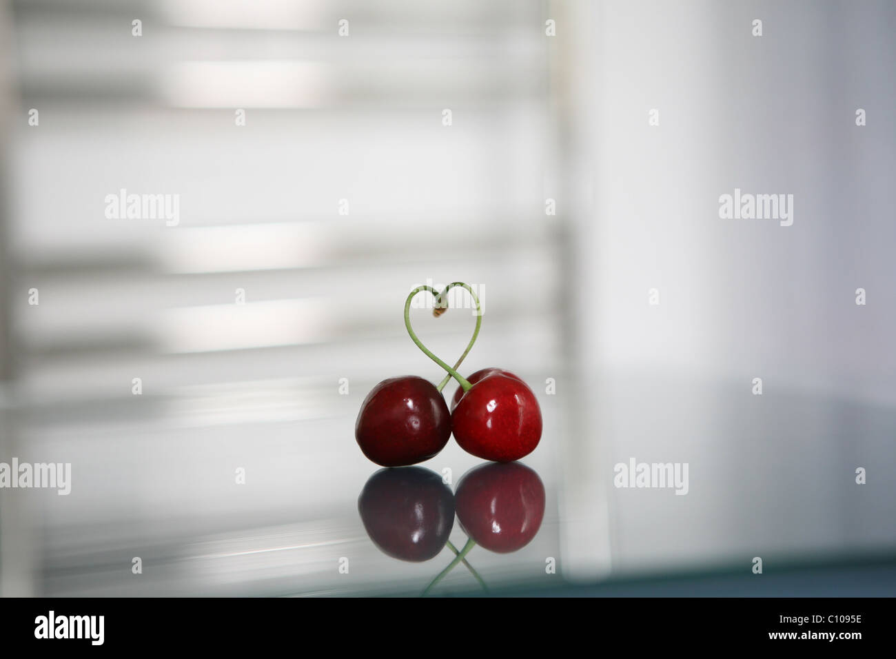 two red cherries with their stalks joined together to form a heart ...