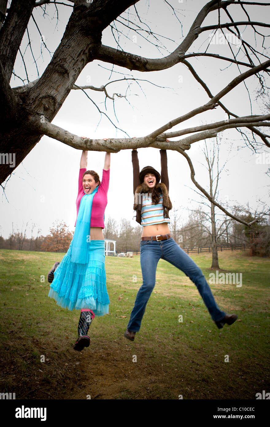 Two teenager girls swing from the limb of a tree on a farm in Virginia ...
