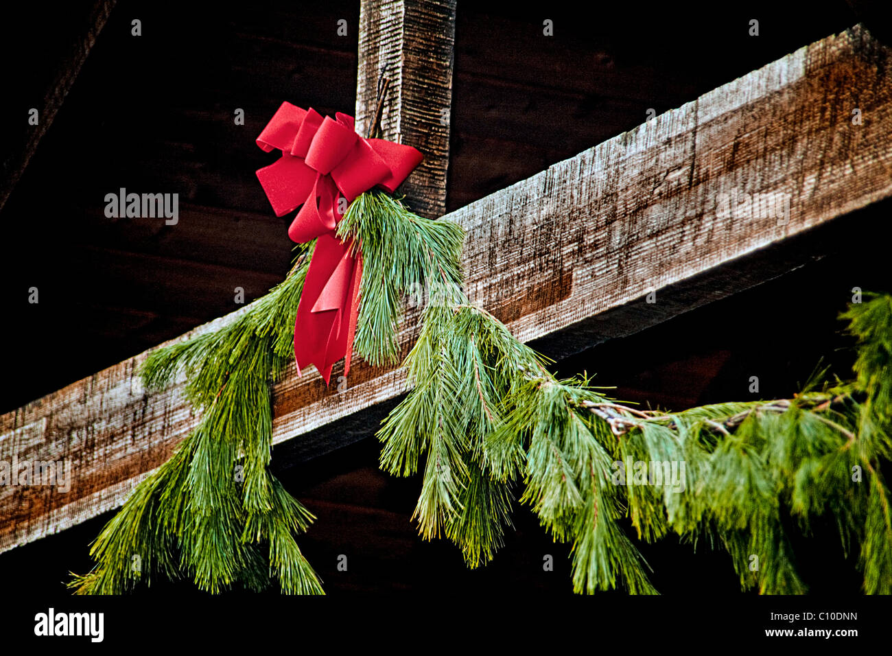 CHRISTMAS BOW AND GREEN GARLANDS HANGING FROM WOOD BEAMS Stock Photo ...