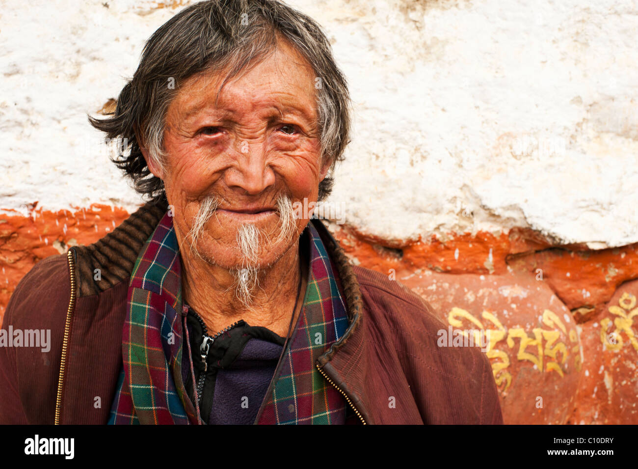 Older Bhutanese man with goatee praying in front of a temple in Central ...