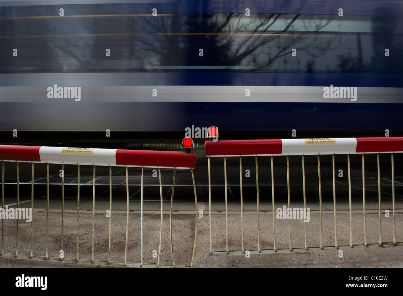 Fast commuter train passes through unmanned automatic level crossing ...