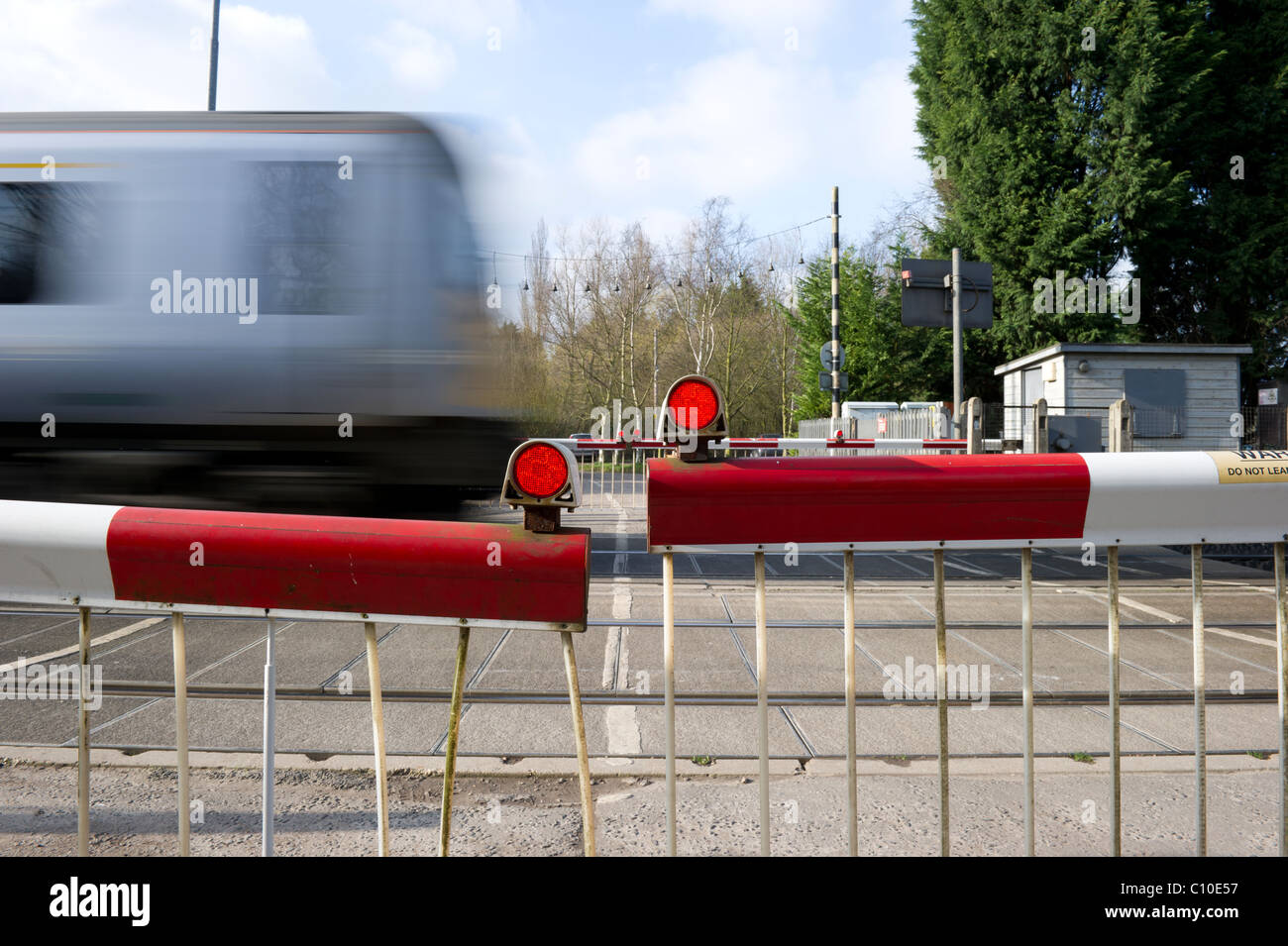 Fast commuter train passes through unmanned automatic level crossing ...