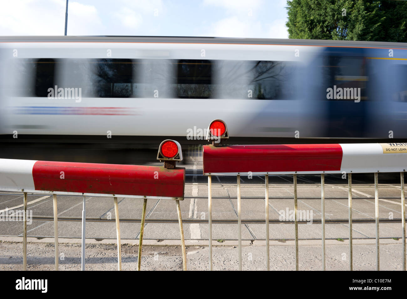 Fast commuter train passes through unmanned automatic level crossing ...