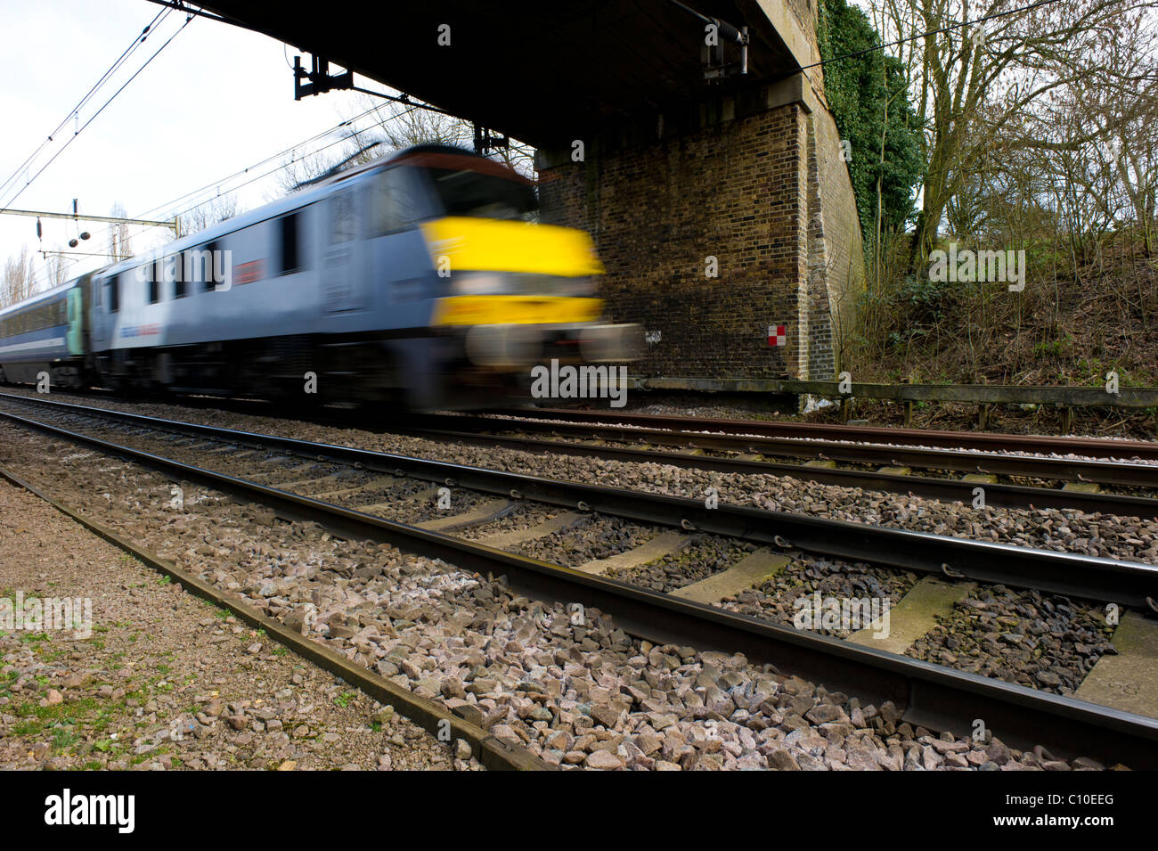 Commuter train passing under bridge at slow shutter speed to give sense ...