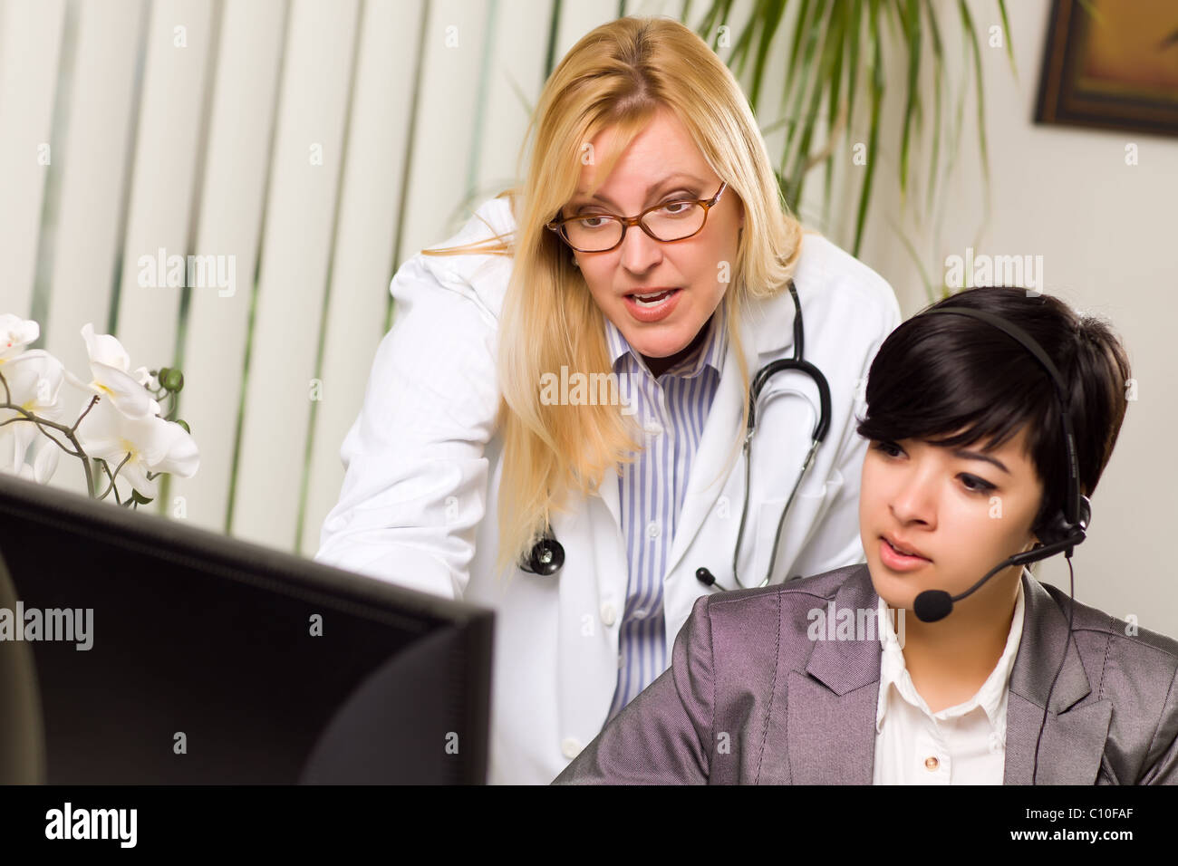 Female Doctor Discusses Work on Computer with Receptionist Assistant in ...