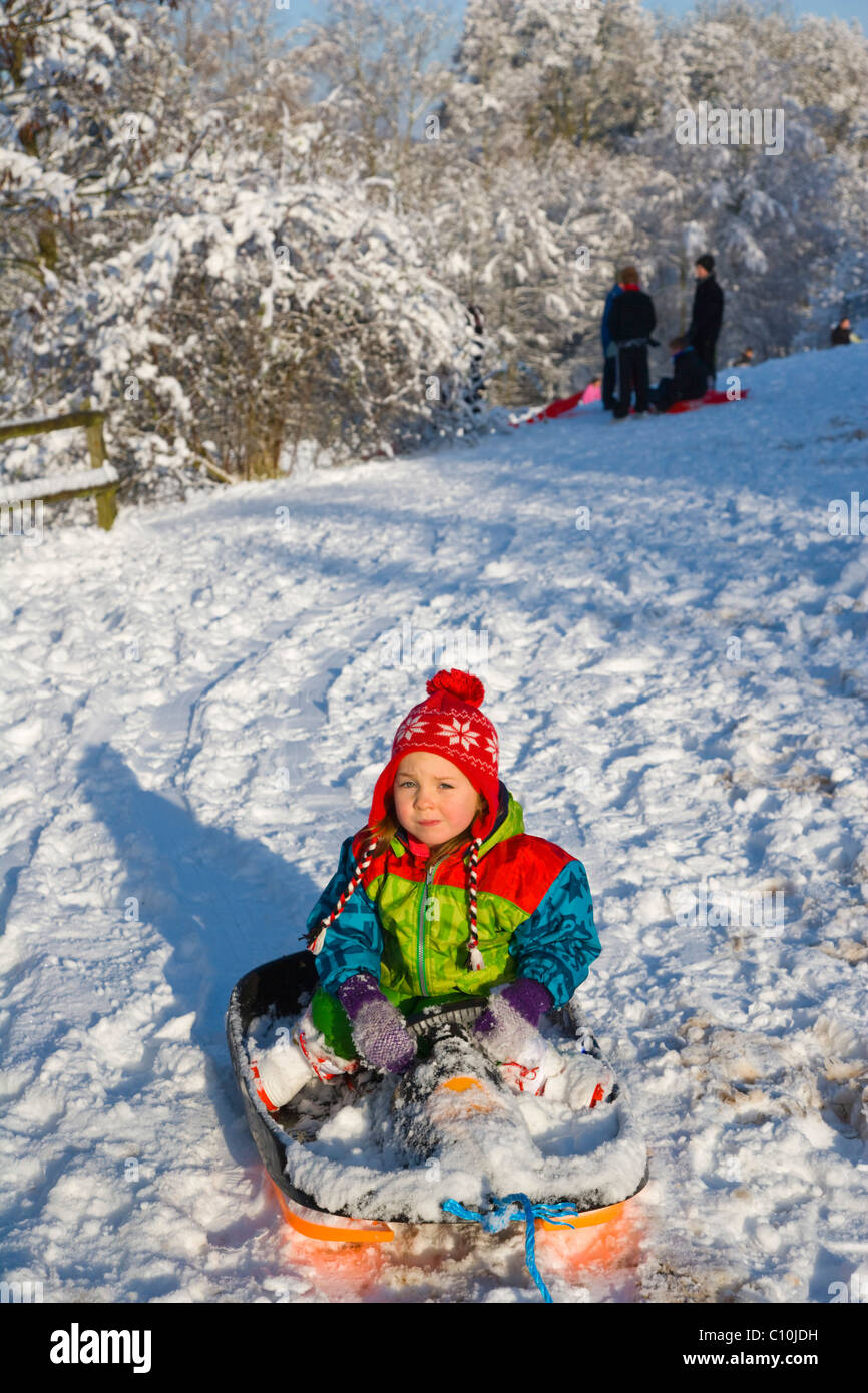 Little girl on a sledge, Burghfield Common, Reading, Berkshire, England ...