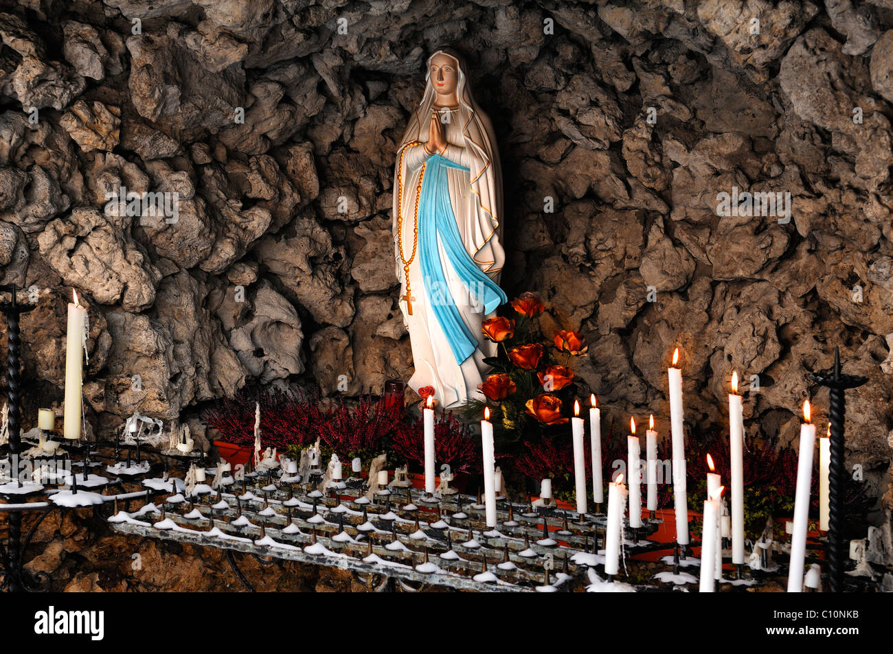 Devotional grotto with Madonna and votive candles in the courtyard of ...