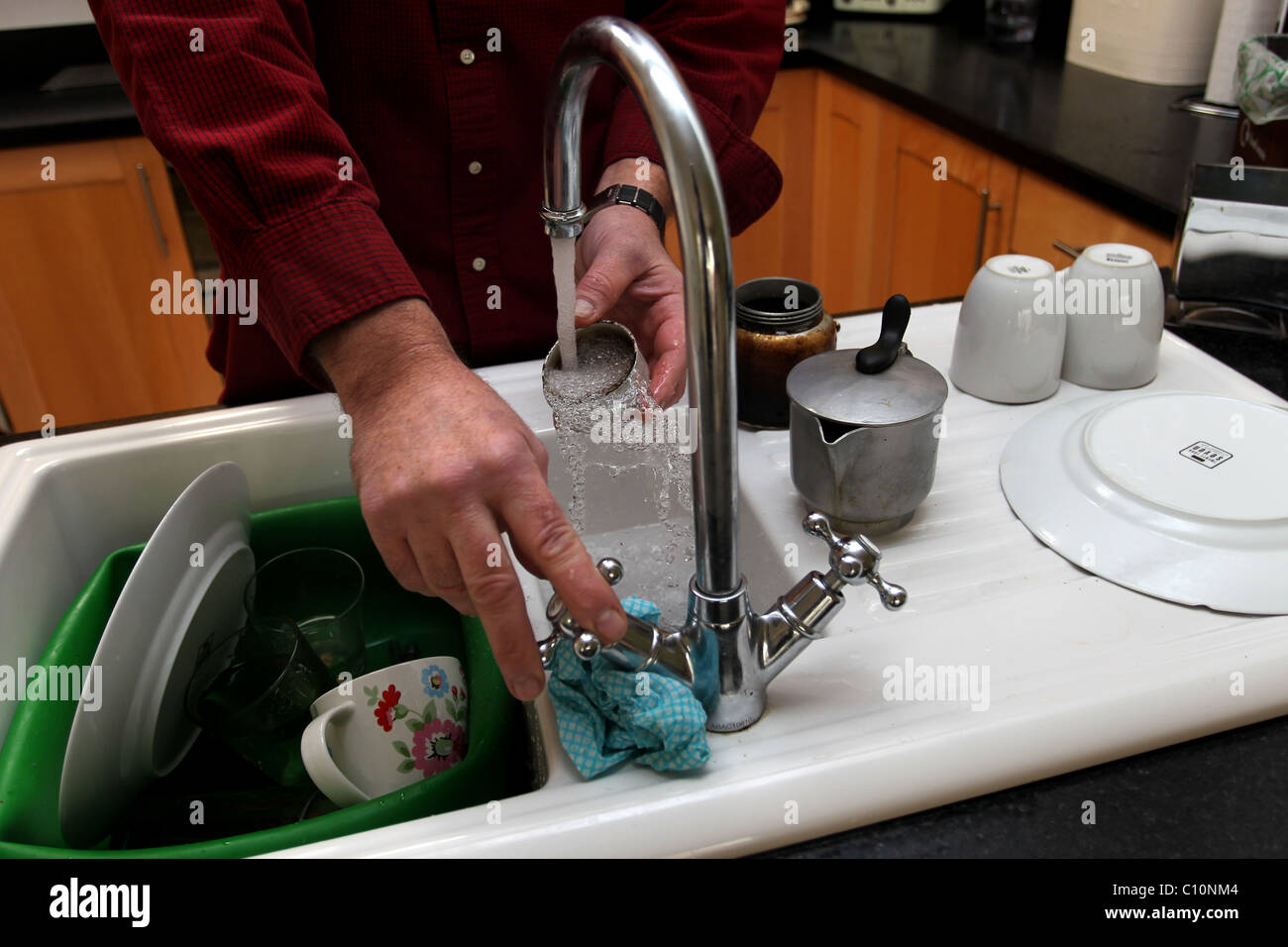 Man washing up a La Cafetiere after making a coffee in his kitchen in ...