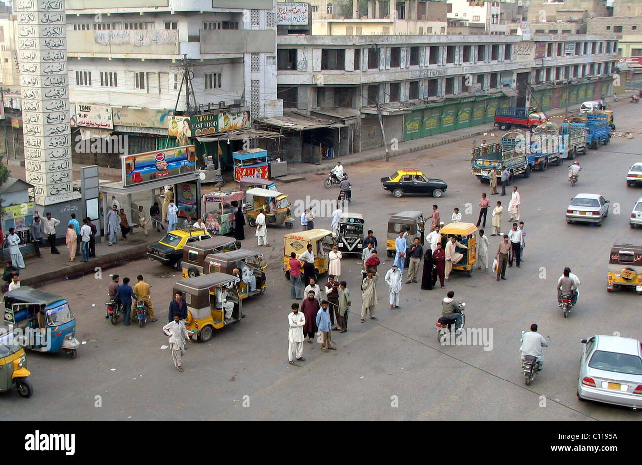 People stand at a bus stop wait for passenger buses at Liaquatabad area ...