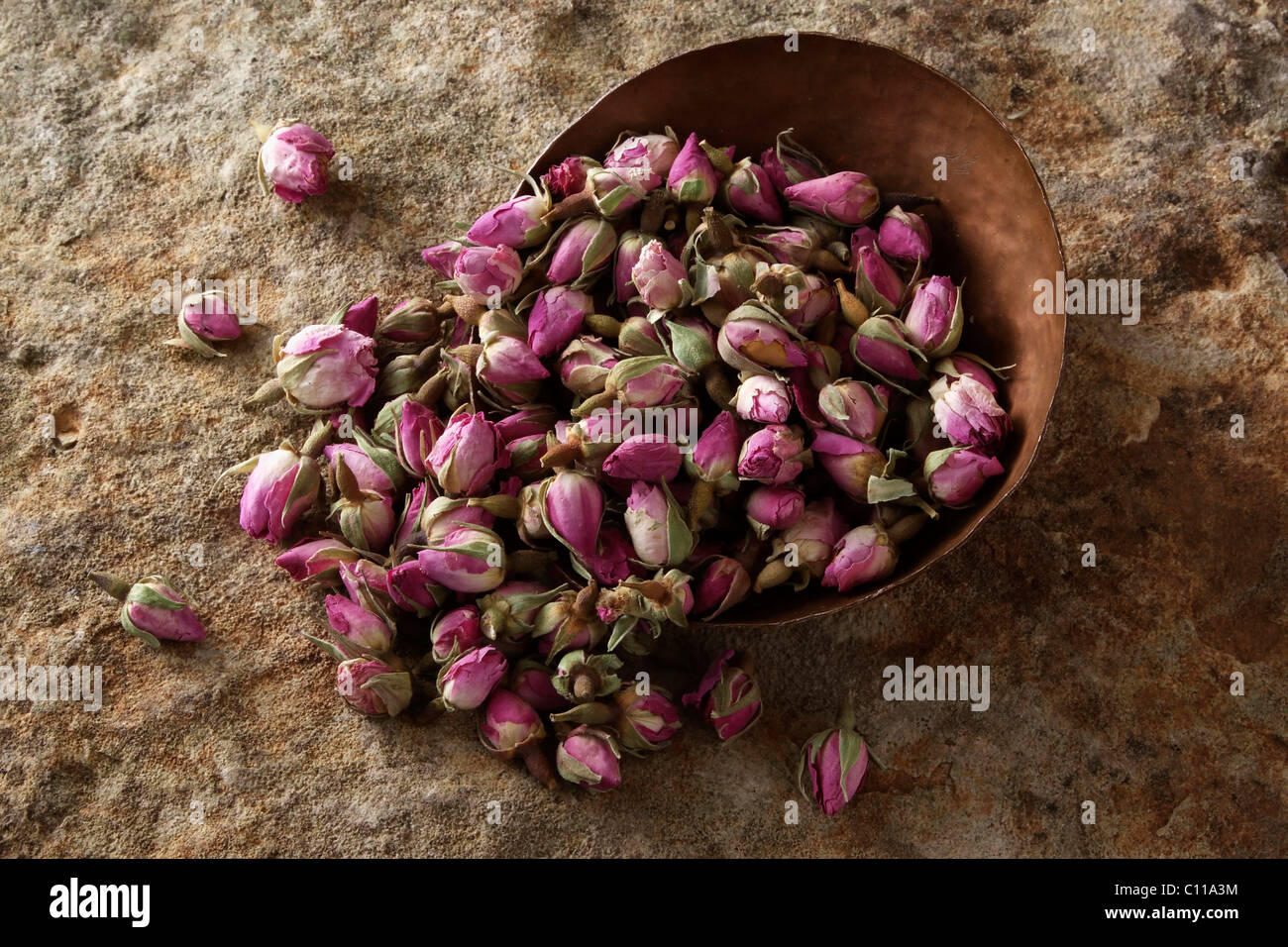 Rose buds (Rosa) in a copper bowl on a stone surface Stock Photo - Alamy