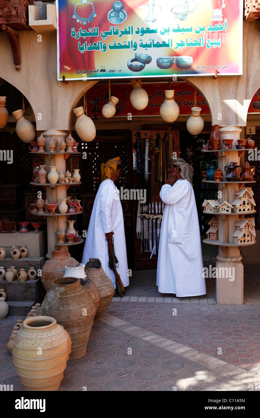 Two Omani men wear traditional clothing at talk at the market (souk) of ...