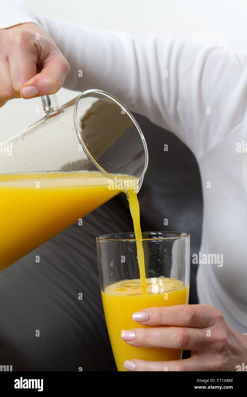 A woman pouring out a glass of orange juice Stock Photo - Alamy