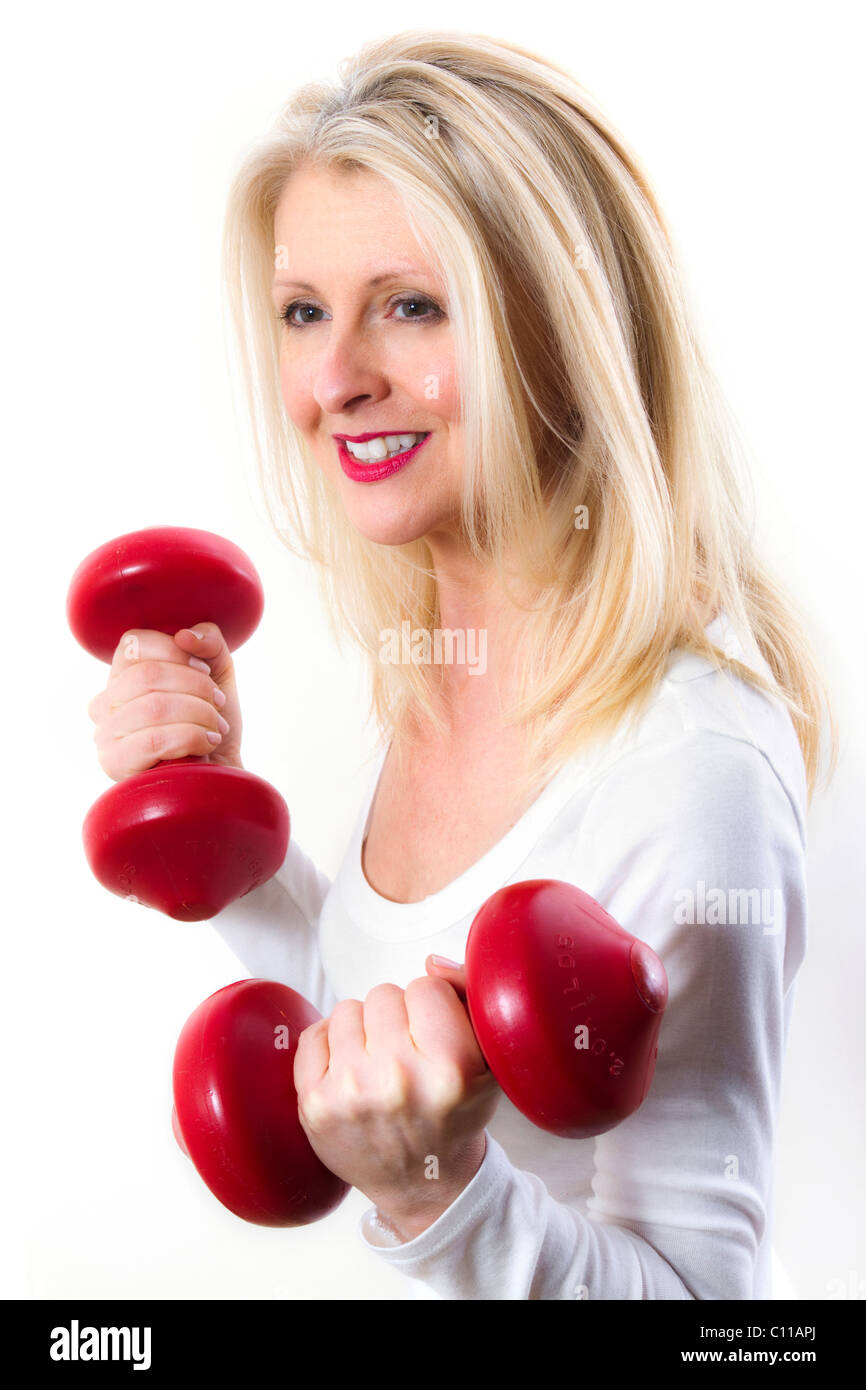 A super fit middle aged woman smiles while working out, using weights ...
