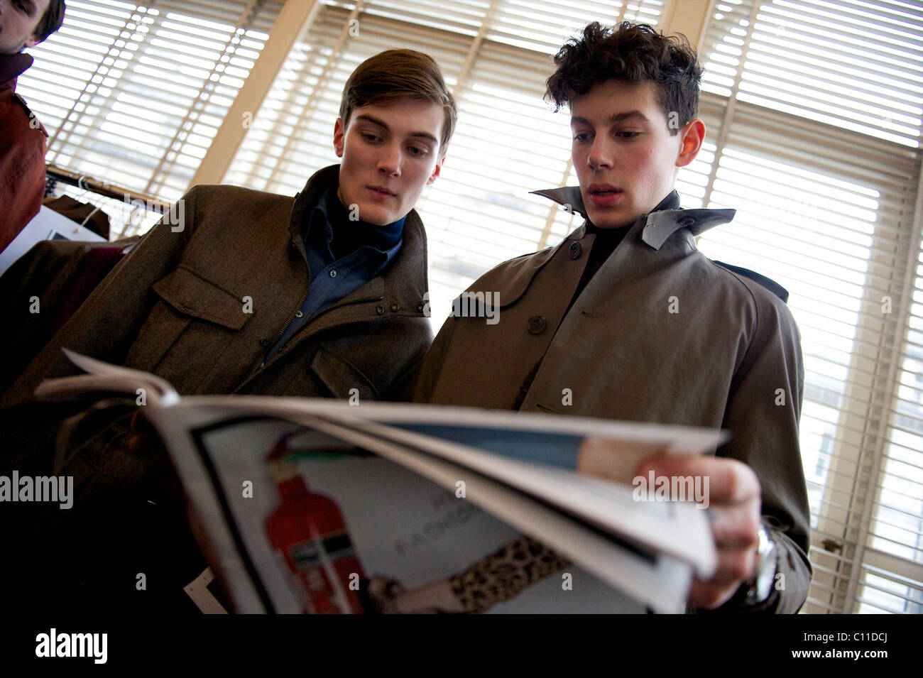 Models leaf through a fashion newspaper backstage before the E. Tautz ...
