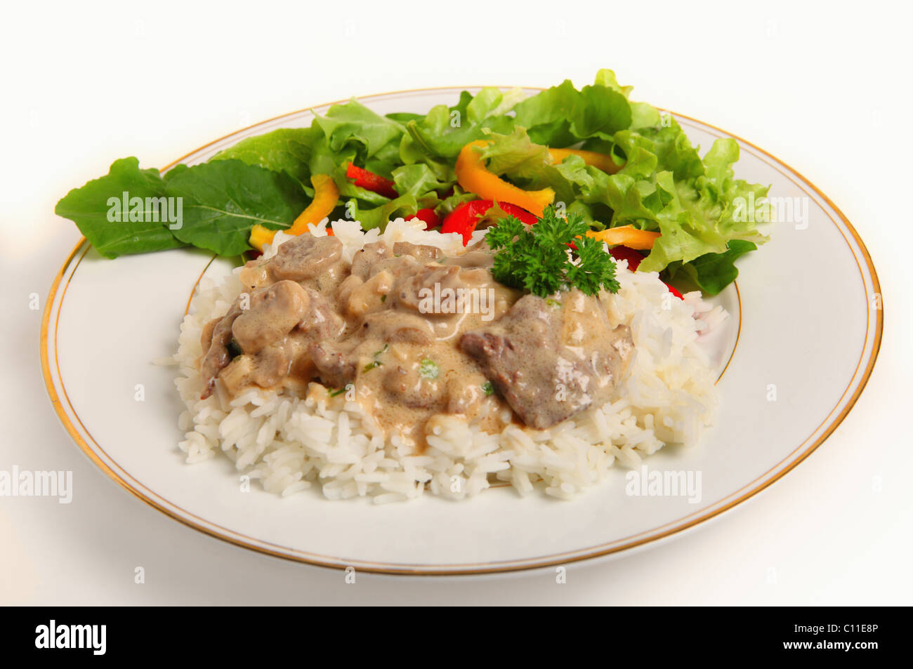 A meal of beef stroganoff with white rice and a salad Stock Photo - Alamy