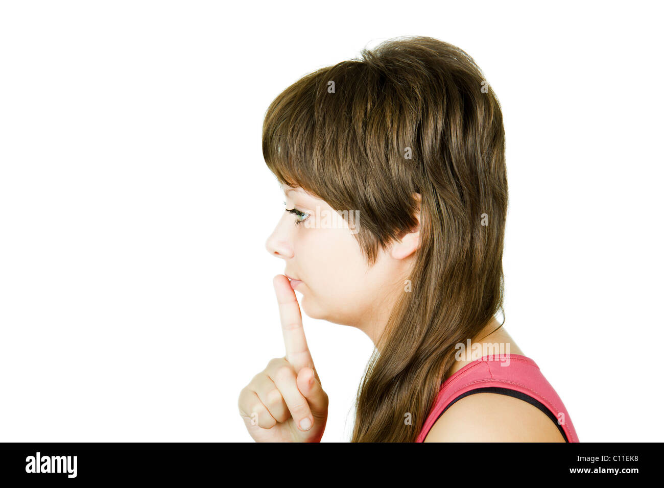 girl keeps the index finger of his lips on an isolated white background ...