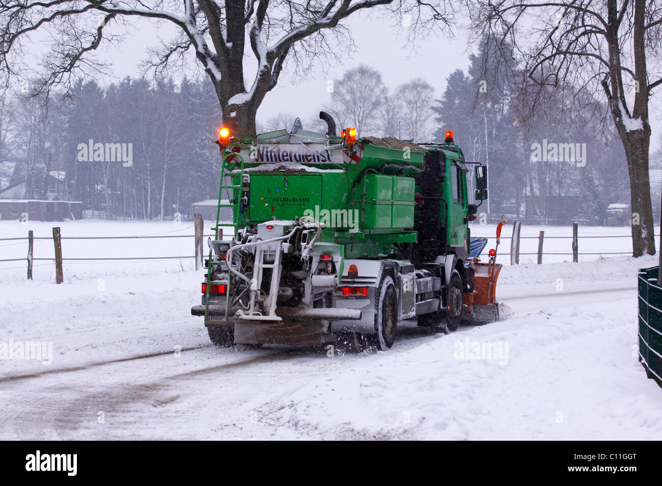 Snow-clearing vehicle clearing the road from snow and ice, spreading ...