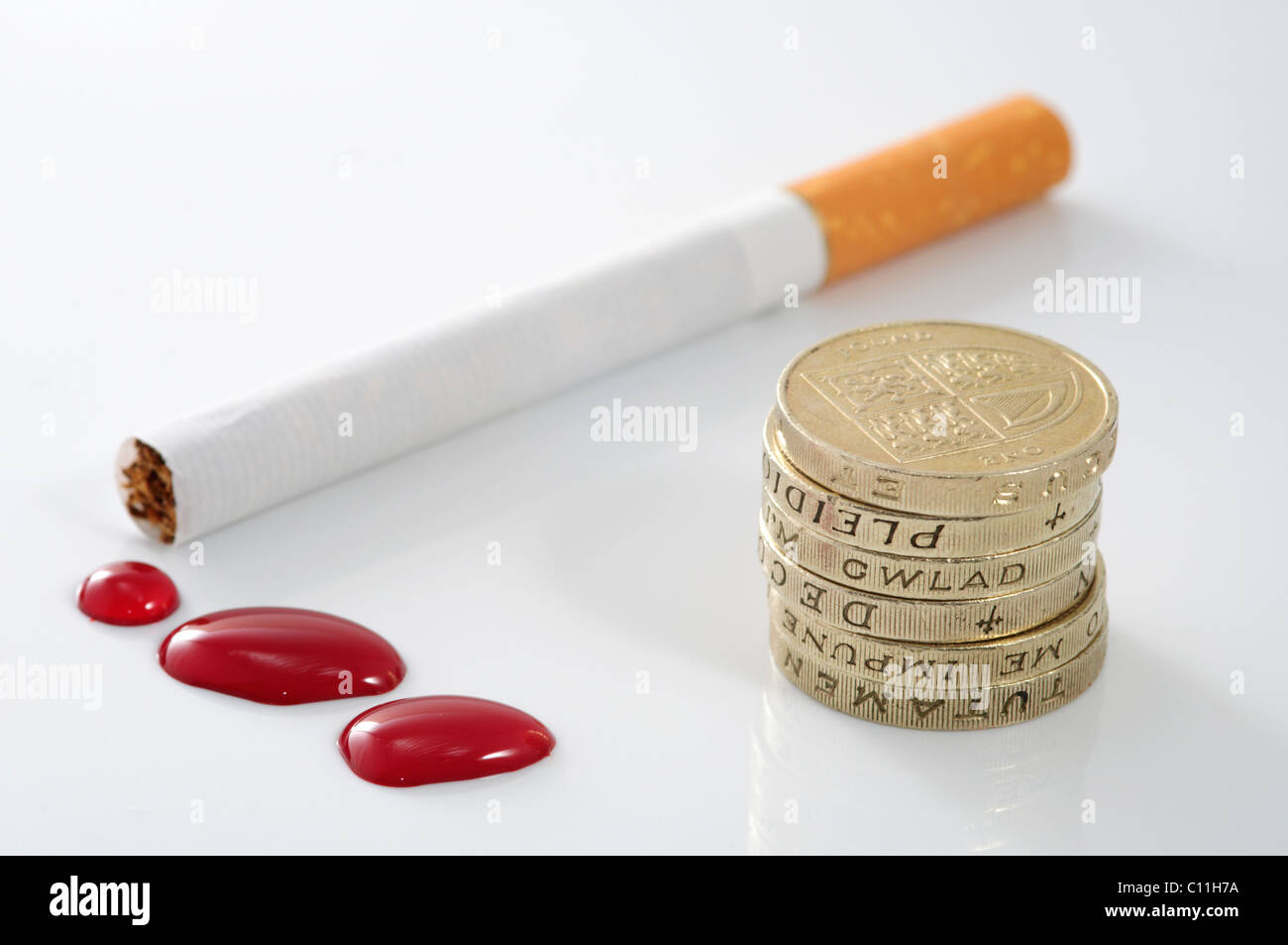 A stack of coins, a cigarette and some droplets of blood Stock Photo ...