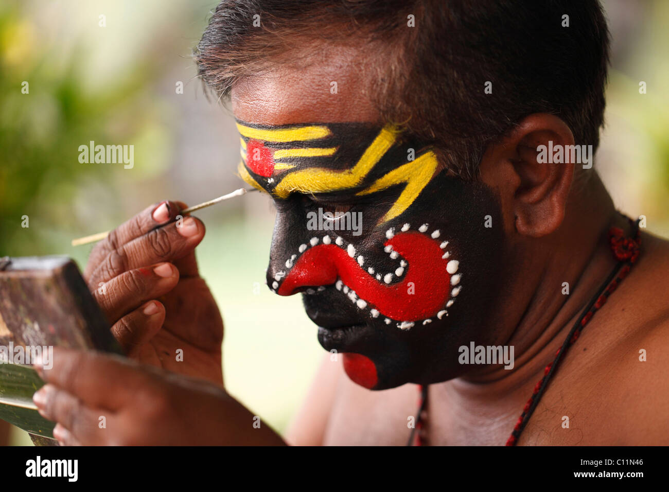 Kathakali dancer doing his make up, Chuvanna Thaadi mask, Kerala ...