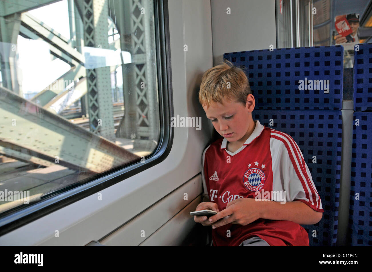 Eight-year-old boy sitting alone in a local train and playing, Germany ...