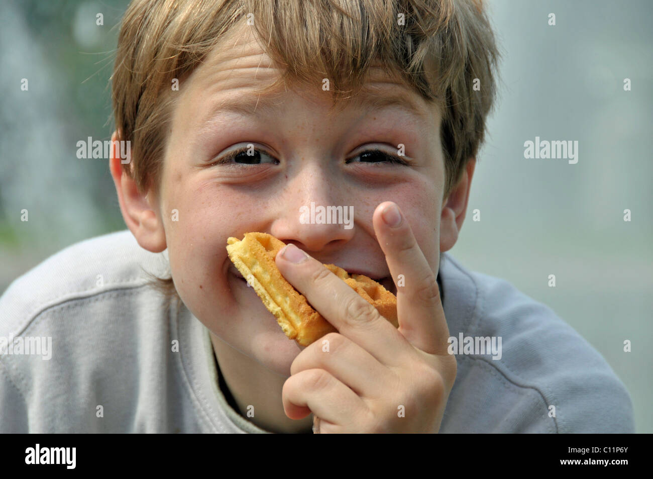 Nine-year-old boy eating a waffle and acting silly, Germany, Europe ...