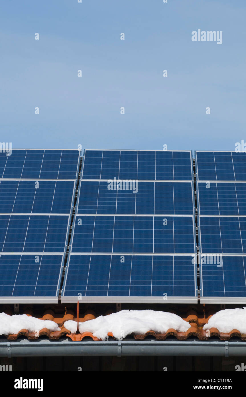 Solar panels on the roof of a house with patches of snow, renewable ...