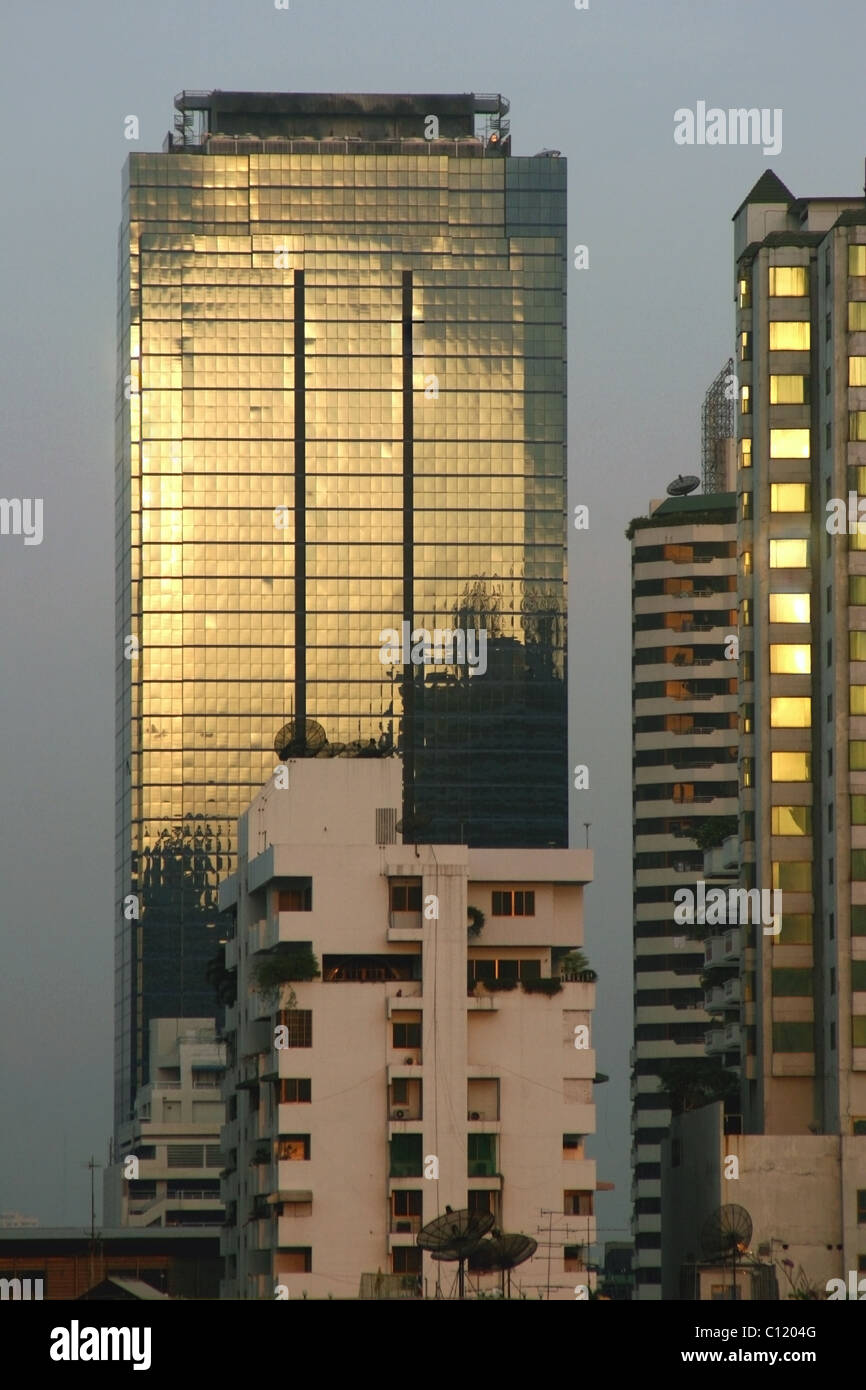 The early morning sun is reflecting off of a tall and modern glass ...