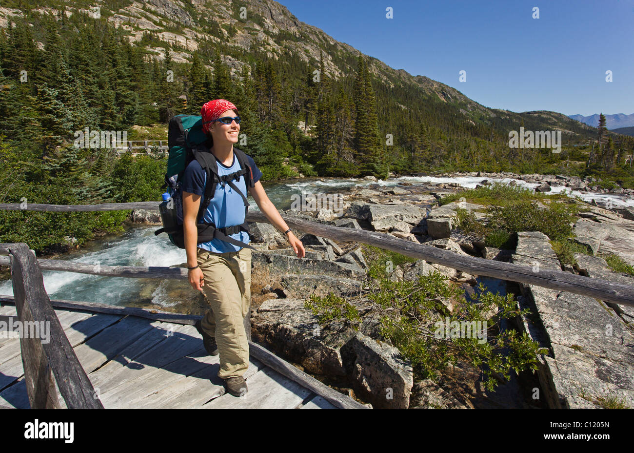 Young woman hiking, backpacking, crossing a wooden bridge, hiker with ...