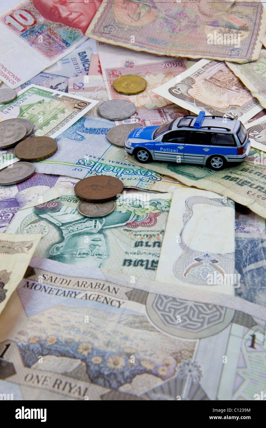 Miniature police car on banknotes and coins from different currencies ...