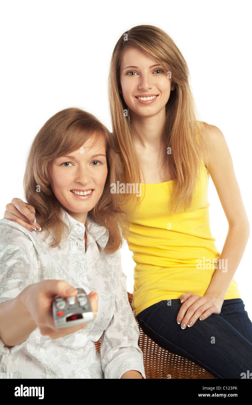 Two smiling pretty blond girls watch TV; isolated on white background ...