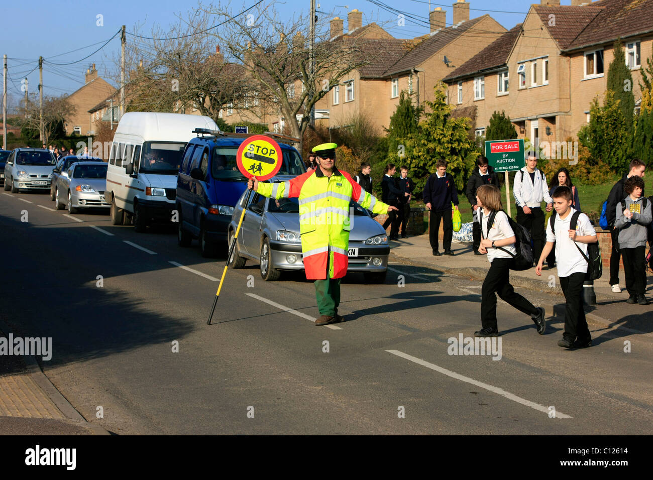 A Lollipop man doing his duty seeing school children across a busy road ...