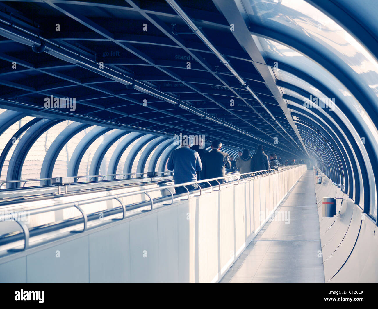 Visitors to the fair on a moving walkway in a connection corridor ...