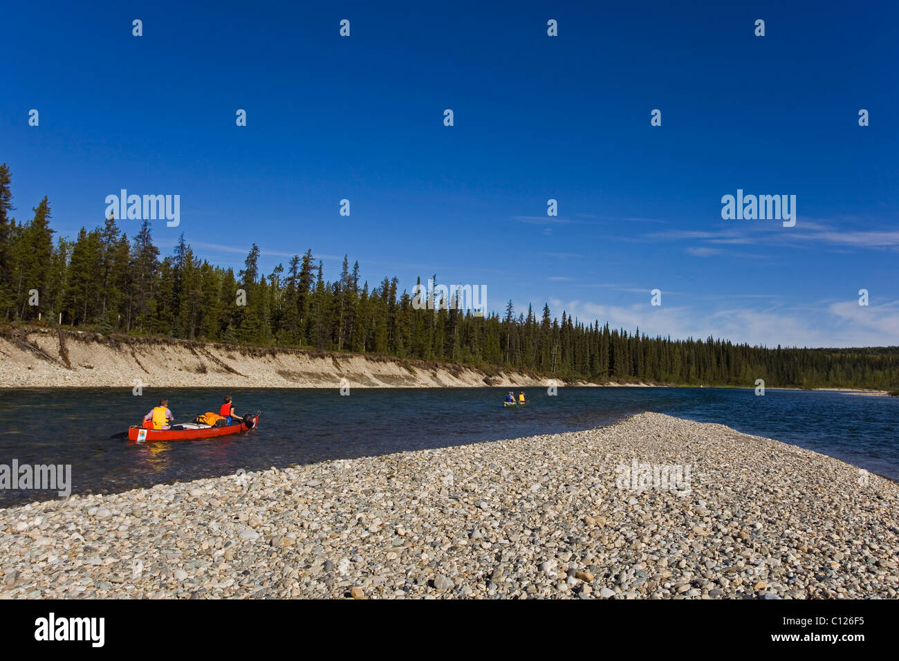 Paddling a canoe along an exposed gravel bar, canoeing upper Liard ...