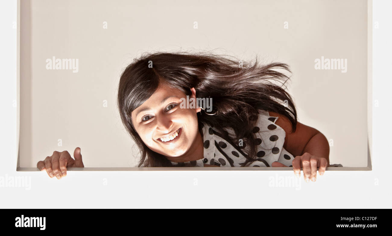 broad smiling indian lady peeking over a ledge Stock Photo - Alamy