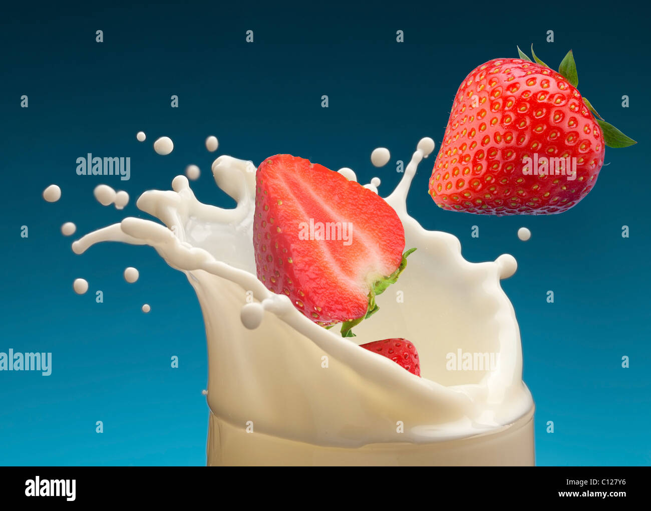 Splash of milk, caused by falling into a ripe strawberry. Isolated on a ...