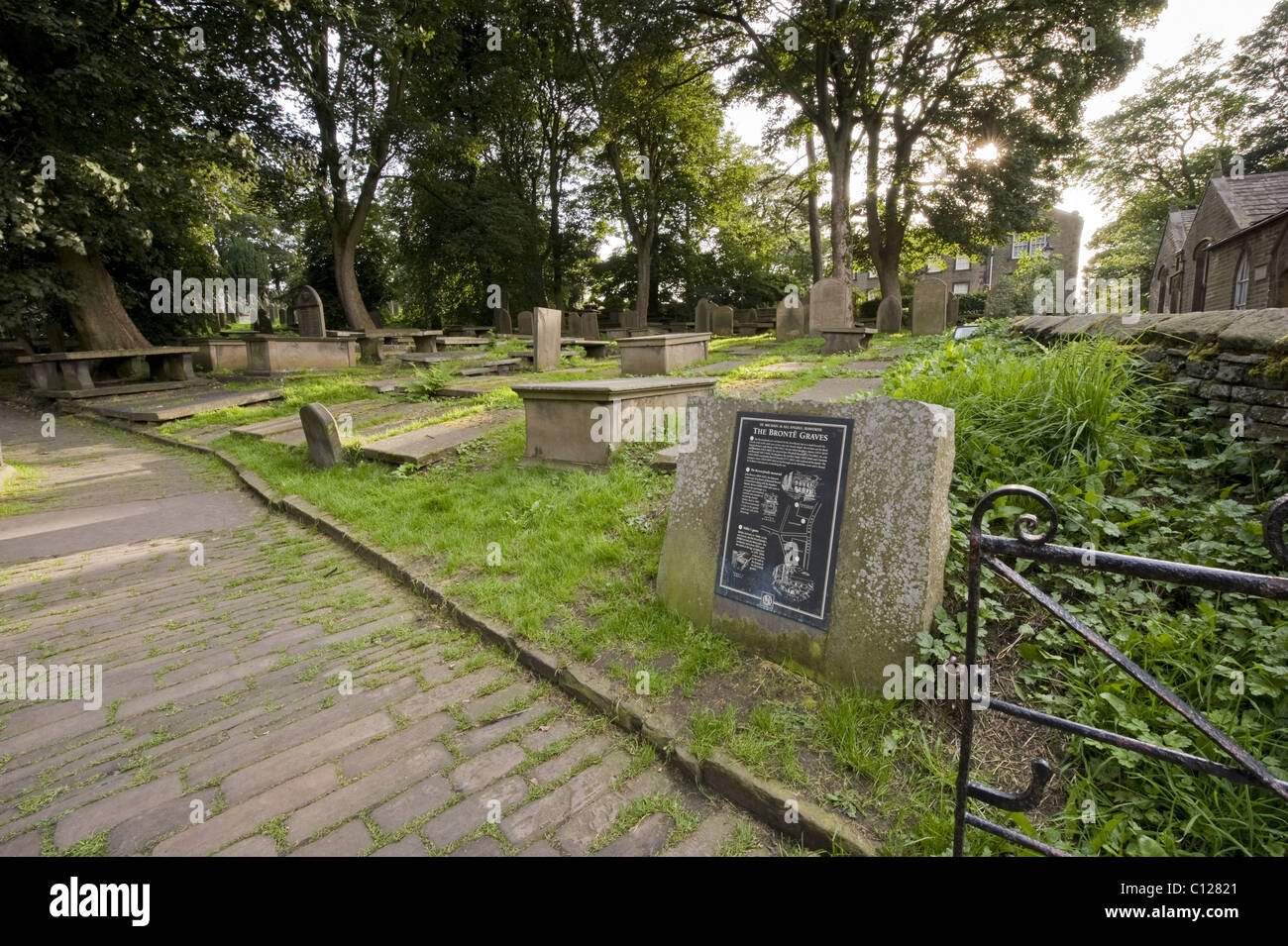 Cobbled graveyard entrance, info board, grave stones & tombs, parsonage ...