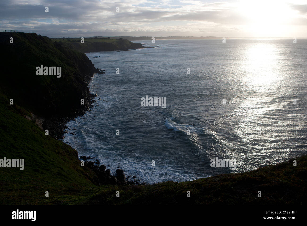 Coastal cliff faces in silhouette and ocean showing tidal action with ...